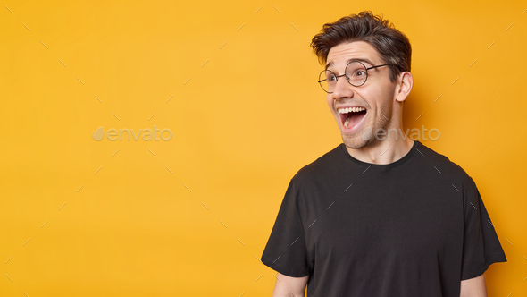 Horizontal shot of happy surprised man keeps mouth widely opened wears ...