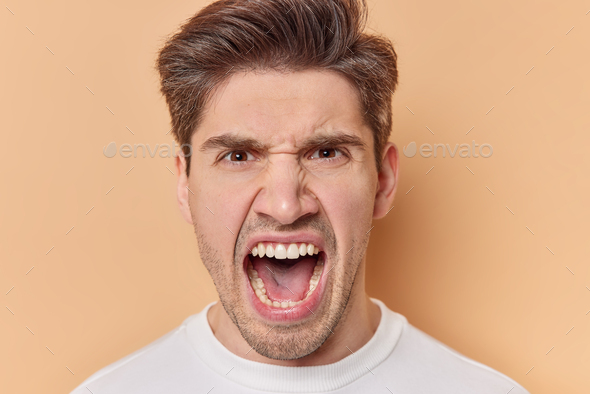 Portrait of outraged angry man keeps mouth opened screams with ...