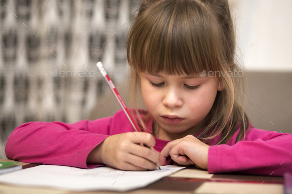 Portrait of cute pretty little serious child girl drawing with pencil ...