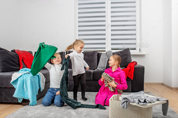 Three children are having fun in room and making mess. Happy childhood ...