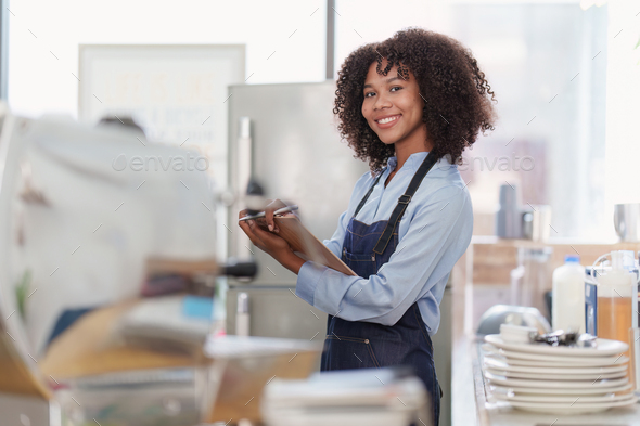 Young Female manager in restaurant with notebook. Woman coffee shop ...