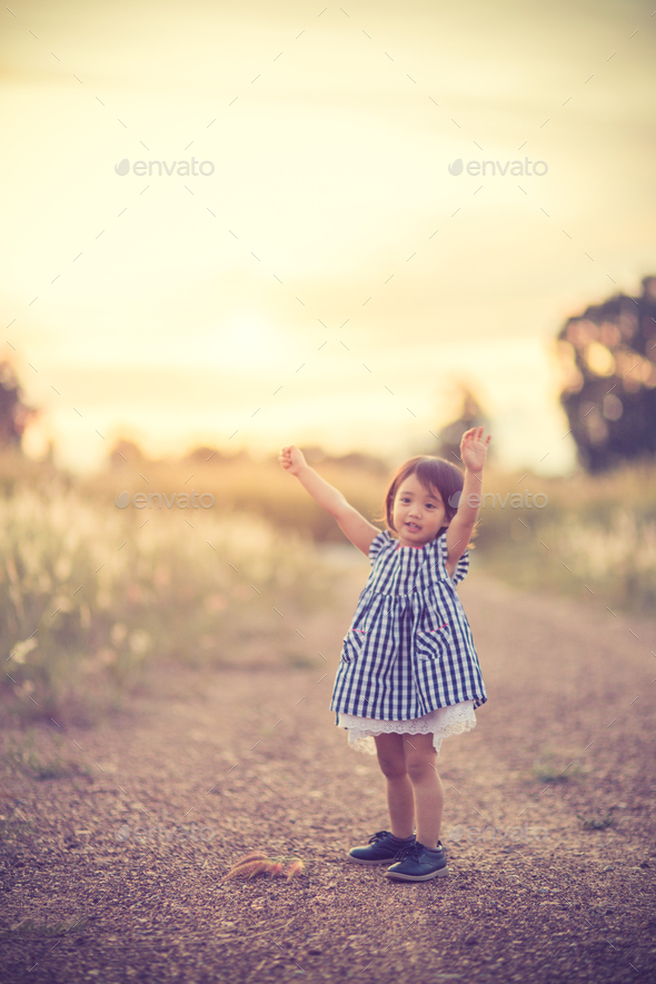 Happy cute kid in a field playing with natural spikes at summer sunset ...