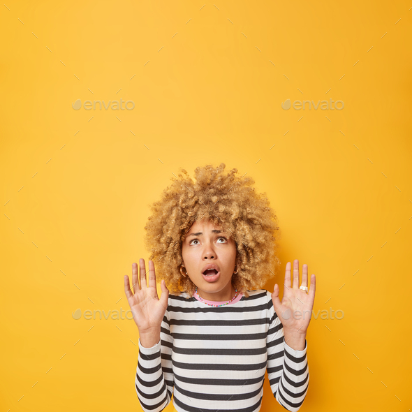 Shocked adult European woman keeps arms up like something falling from ...