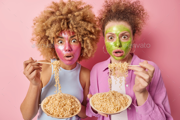 Astonished women with curly hair apply beauty masks on face eat ...