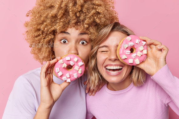 Photo of two female best friends hold delicious doughnuts with ...