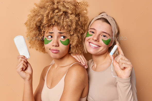Photo of two women friends pose with hygiene products choose between ...