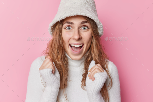 Pretty surprised European woman exclaims gladfully raises hands stares ...