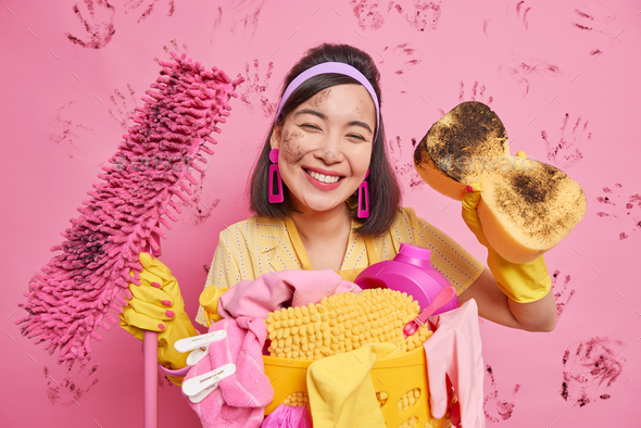 Cleaning service concept. Positive Asian woman poses with basket of ...