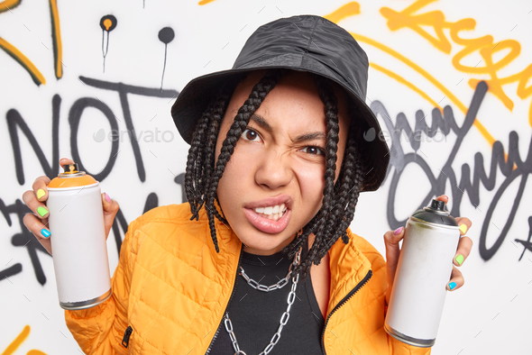 Trendy teenage girl with braided hair clenches teeth has cheeky ...