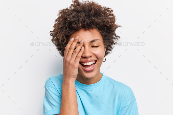 Horizontal shot of cheerful woman with curly hair makes face palm ...