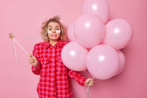 Scared terrified woman holds magic wand and bunch of inflated balloons ...
