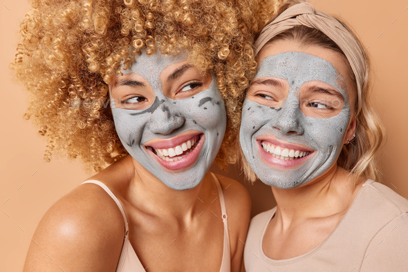 Close up portrait of two cheerful young women apply mud mask smile ...