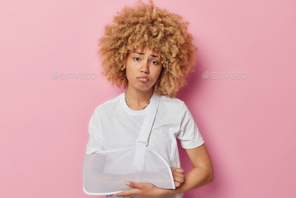 Unhappy woman with curly blonde hair has broken arm wears sling got ...