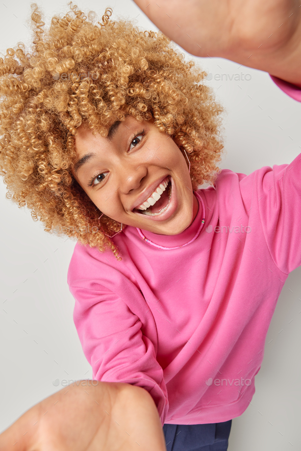 Cheerful millennial girl smiles happily keeps arms outstretched poses ...