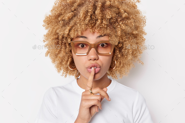 Headshot of surprised mysterious woman makes silence gesture shushes ...