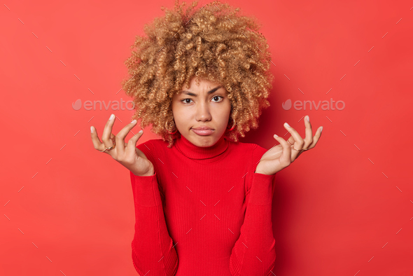 Indifferent hesitant woman spreads hands shrugs shoulders has unaware ...