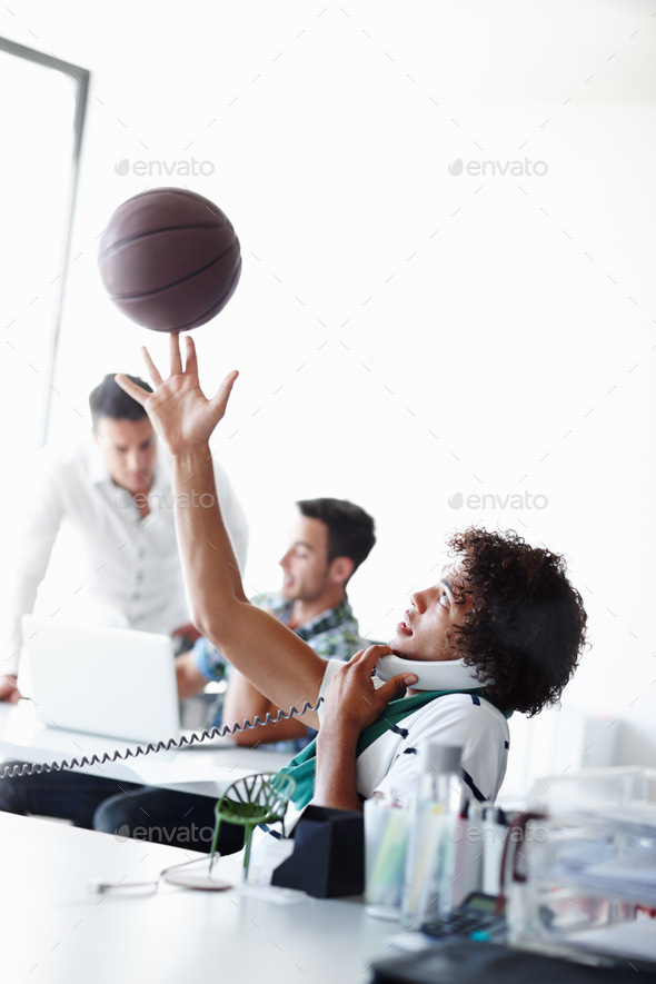 A young man playing with a basketball while sitting in the office Stock ...
