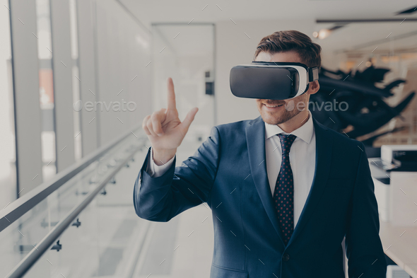Smiling business professional in suit wearing VR headset on head using ...