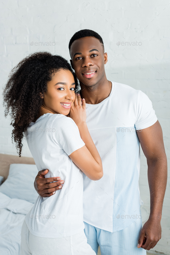 happy african american woman cuddling to handsome boyfriend, looking at ...