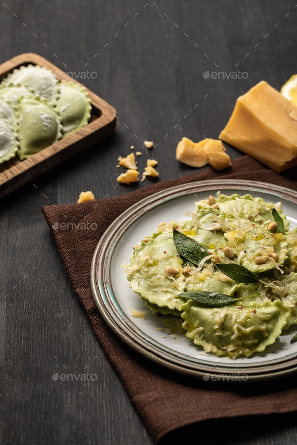green ravioli with melted cheese, pine nuts and green sage leaves in ...