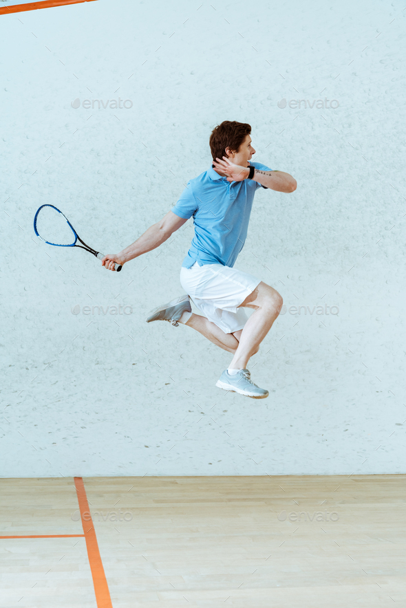 Sportsman in polo shirt jumping while playing squash in four-walled ...