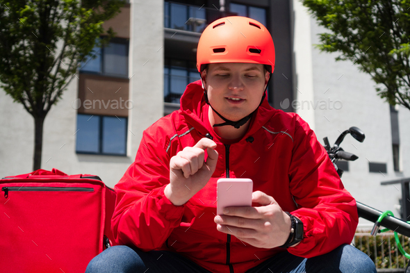 Delivery man checking food order with smartphone Stock Photo by ...
