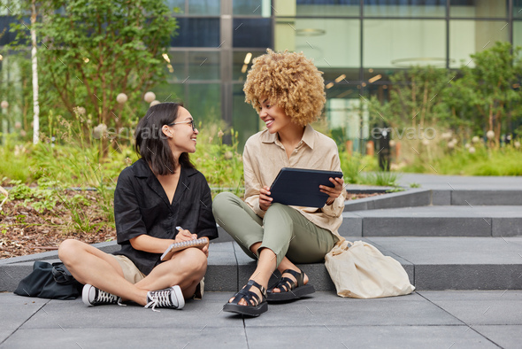 Two young girls have collaboration meeting use touchpad and takes notes ...