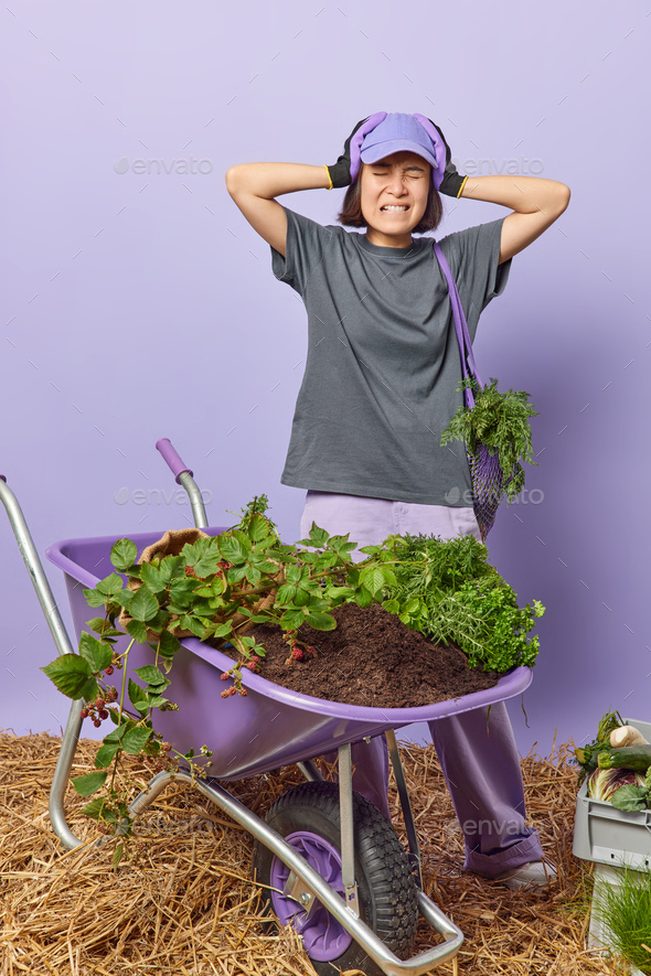 Bothered tired gardener suffers from severe headache wears casual clothes stands near ...