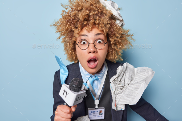 Shocked curly female TV reporter makes reportage stares stunned with ...