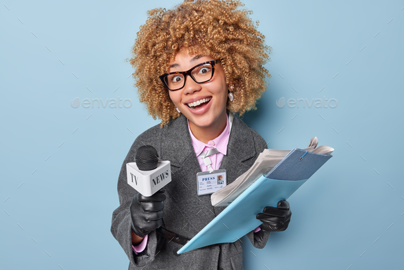 Cheerful female correspondent smiles broadly prepares reportage or ...