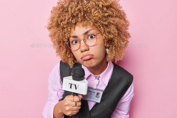 Discontent curly female reporter broadcasts news event frowns face ...
