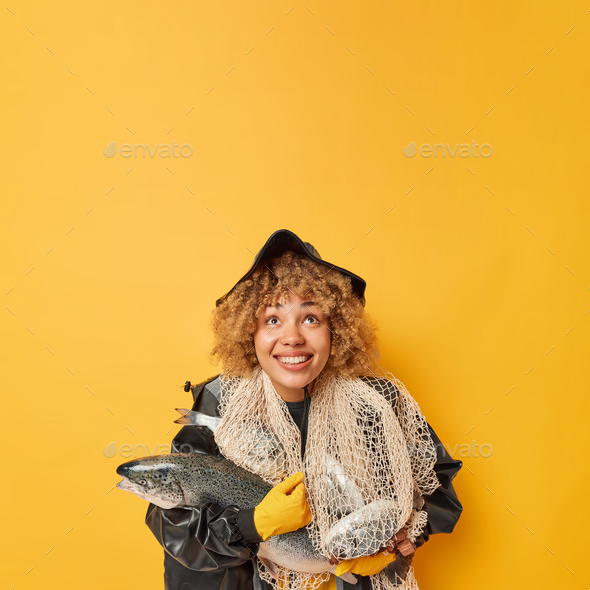 Vertical shot of positive successful curly haired woman poses with huge ...