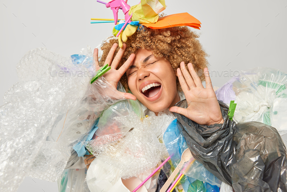 Emotional curly haired woman activist covered with plastic garbage ...