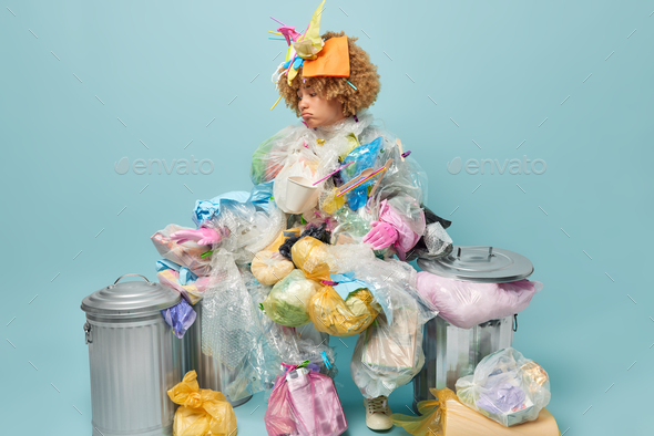 Female eco activist surrounded by much garbage and rubbish bins upset ...