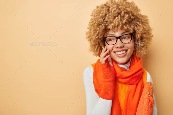 Horizontal shot of good looking woman smiles happily touches face ...