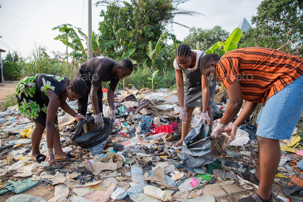 Four young adults collect garbage in an illegal open-air landfill in ...