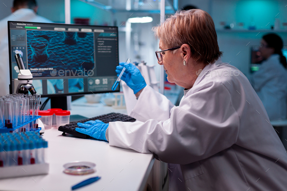 Scientist typing results of science analysis holding test tube with ...
