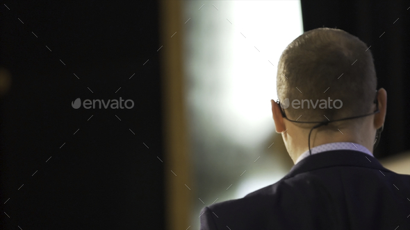 Rear view of speaker in suit giving a talk on corporate Business ...