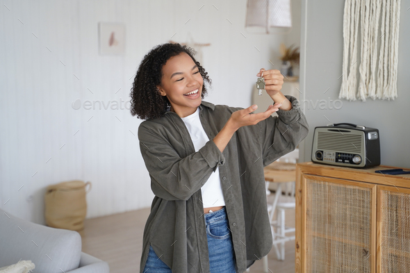 Joyful biracial teen girl tenant homeowner shows home keys to new first ...