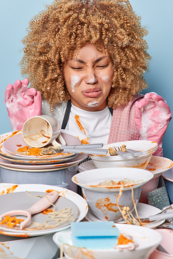 Displeased woman with curly hair foam on face looks with aversion at ...