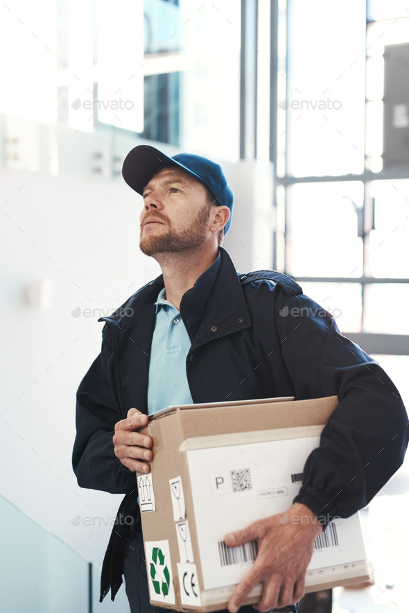 Shot of a handsome delivery man heading up a flight of stairs with a ...