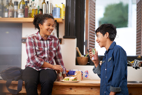 Shot of two young teenagers enjoying a snack together in the kitchen ...