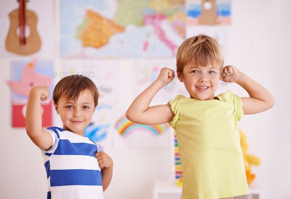 Two young boys flexing their muscles while standing in their bedroom ...