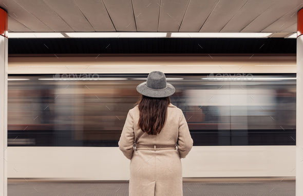 Back view of woman standing on underground train platform in front of ...
