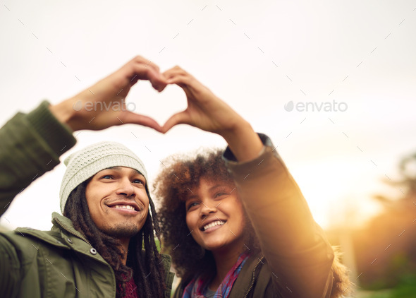 Shot of two friends making a heart shape with their hands while ...
