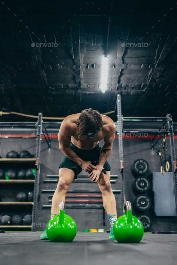 Vertical photo of a tired man training in a gym Stock Photo by riderfoot
