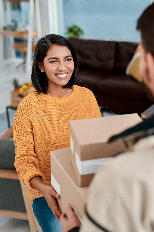 Shot of a young woman receiving a package from a delivery man at home ...