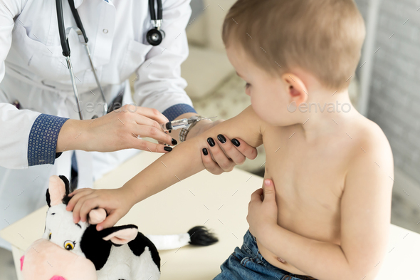 Doctor pediatrician giving child an intramuscular injection in arm ...