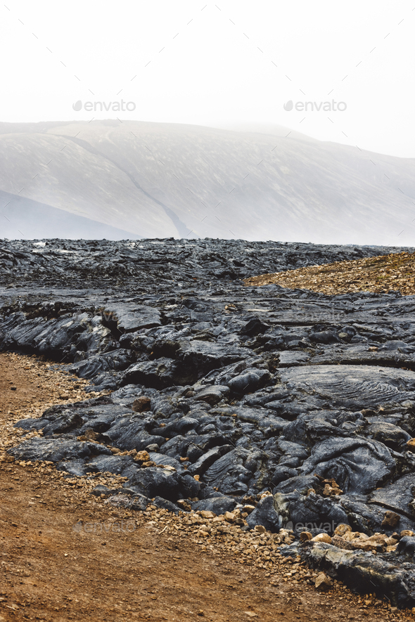 Vertical photo os cooled lava forming black volcanic rocks on the ...