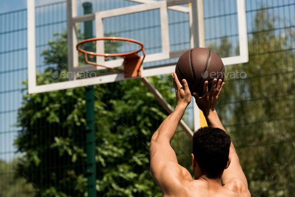 back view of basketball player throwing ball in basket at basketball ...